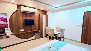 Quarto de hotel com cama, escrivaninha, cadeira, televisão e ar condicionado.