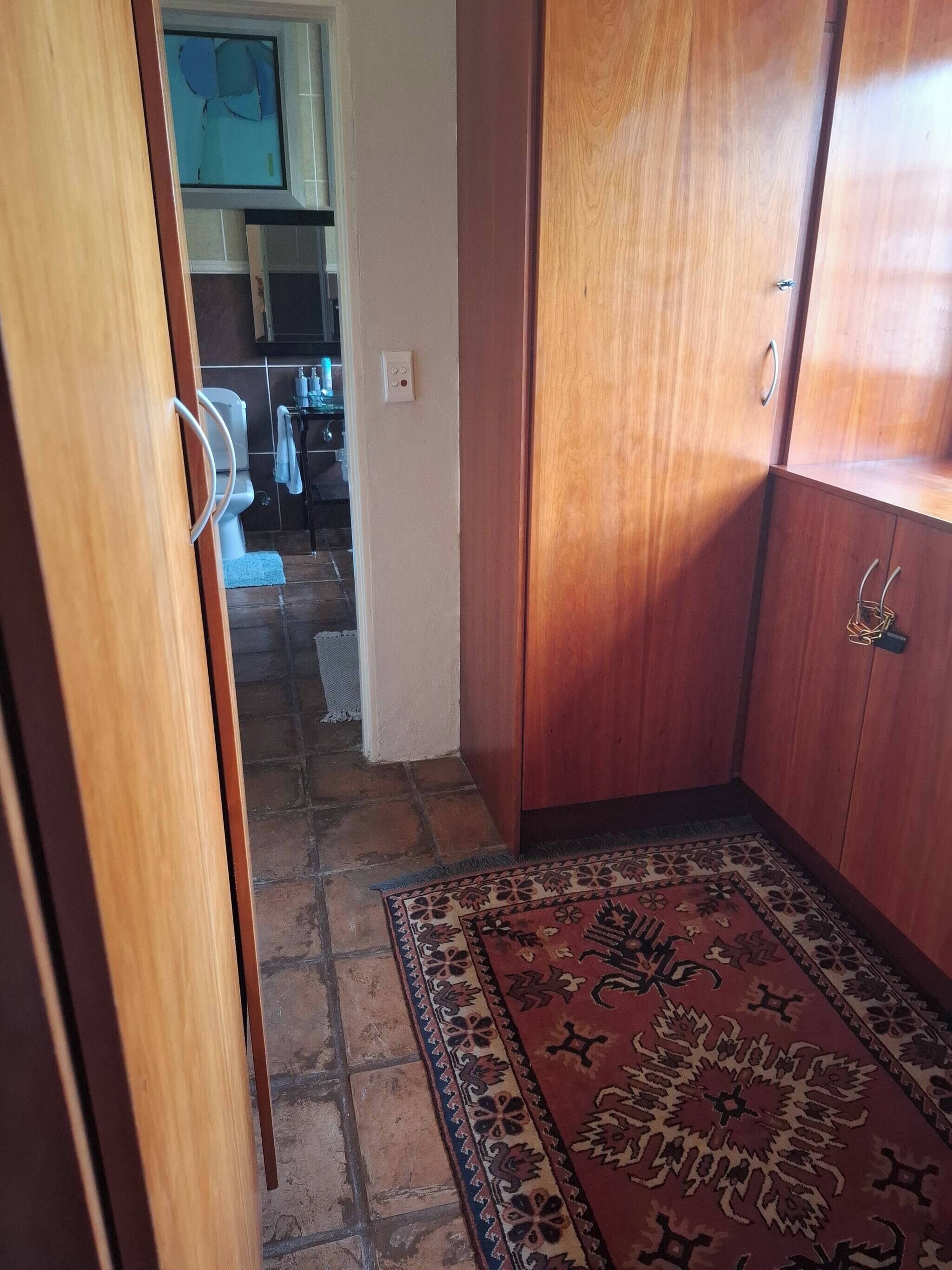 Um guarda-roupa de madeira, um tapete estampado e um chão de azulejos.