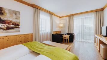 Quarto de hotel com uma cama, uma escrivaninha com televisão, uma cadeira, uma mesa pequena e um quadro na parede.