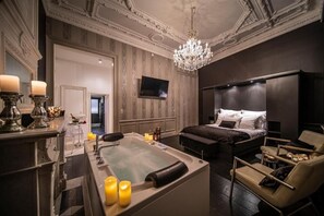 Um quarto luxuoso com uma cama grande, uma banheira e um candelabro.