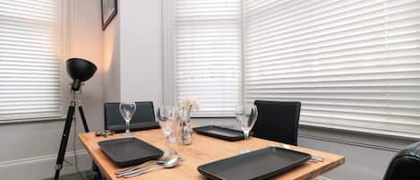 Uma sala de conferência com uma mesa de madeira, cadeiras pretas, um abajur de tripé e um quadro na parede.