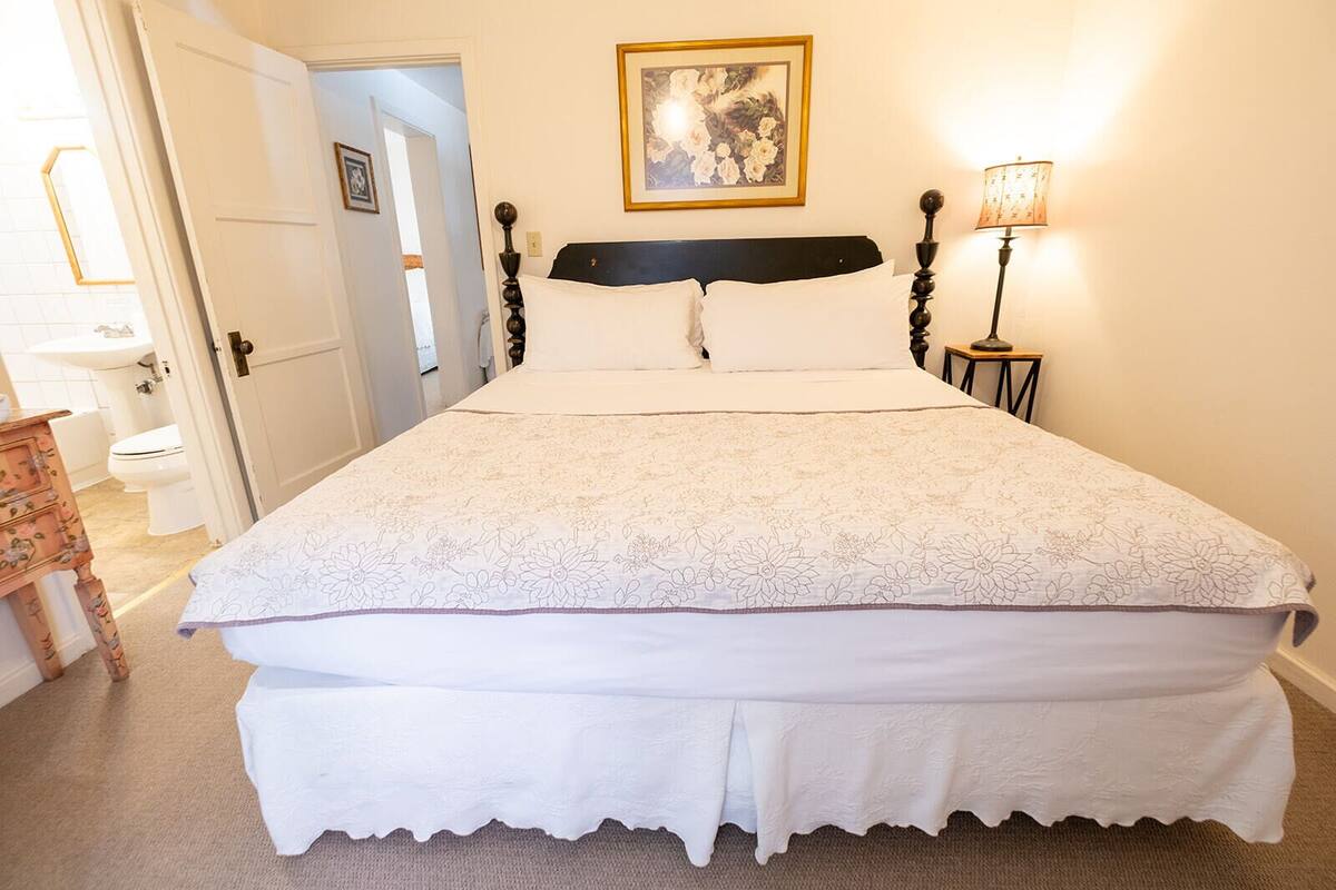 Uma cama com colcha florida, um abajur e um quadro na parede.