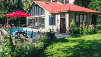 Uma casa com piscina, área de estar externa e um guarda-sol vermelho.