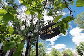 Placa indicando 'Beaumont Inn', com um lampião e árvores ao fundo.