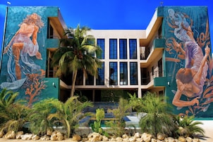Hotel com design arquitetônico moderno, apresentando um pátio central com piscina e palmeiras.