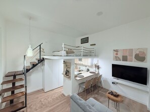 Um interior moderno com beliche, área de refeições, televisão e escada.
