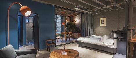 Quarto de hotel moderno com cama, área de estar e pequena mesa de jantar.