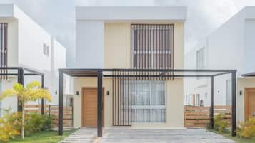 Um edifício residencial moderno com entrada central, varanda coberta e um jardim bem cuidado.