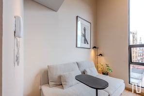 Uma sala de estar moderna com um sofá cinzento, uma mesinha, uma obra de arte emoldurada, um abajur e uma planta em vaso.