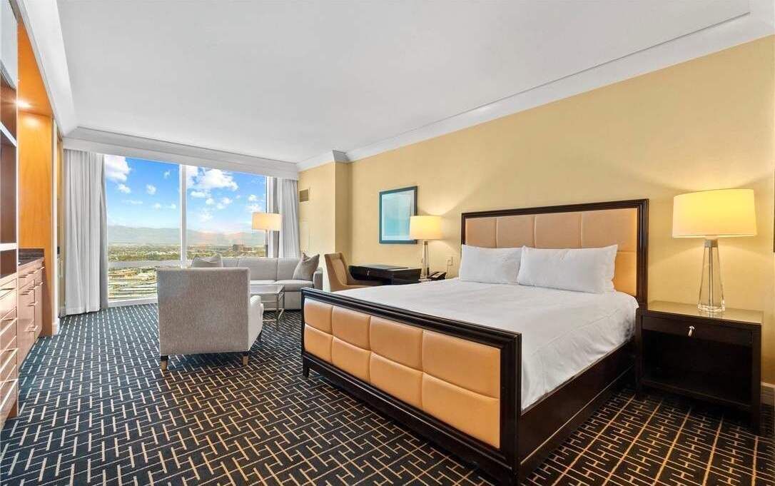 Quarto de hotel com uma cama grande, uma escrivaninha, uma cadeira e vista para a cidade.