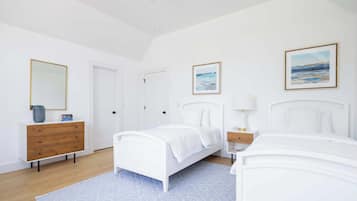 Quarto com duas camas, cômoda, mesa de cabeceira e uma porta.