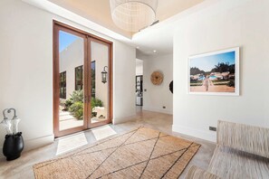 Um interior moderno com uma grande porta de vidro deslizante que dá para um jardim, um tapete estampado e um quadro na parede.