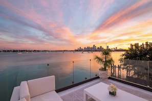 Piscina no terraço com vista para o horizonte urbano ao pôr do sol.