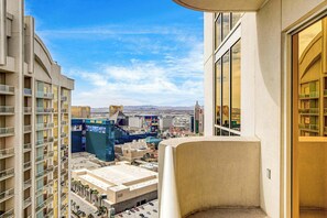 Quarto de hotel alto com vista para a paisagem urbana, incluindo um cassino e montanhas ao longe.