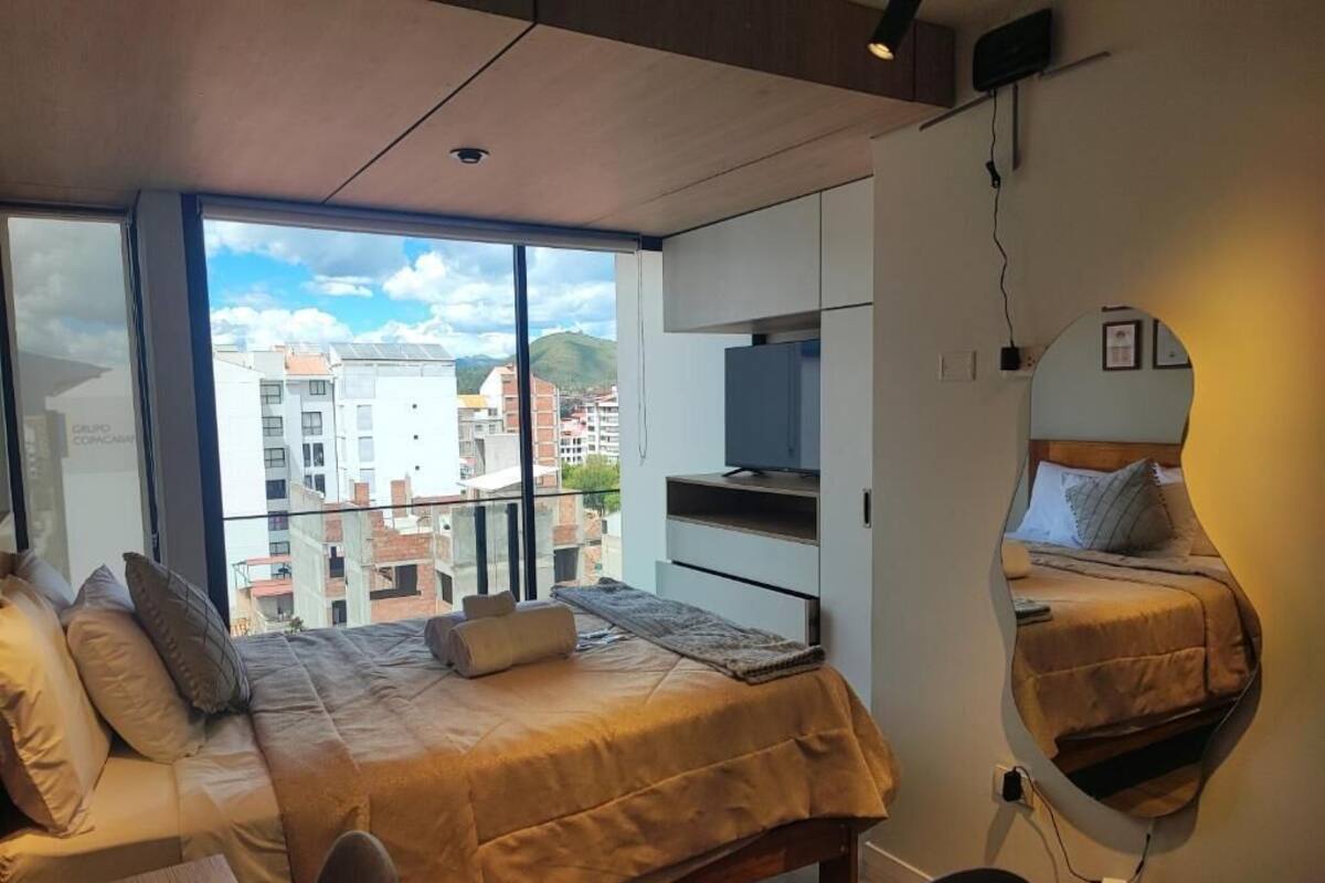 Quarto moderno com cama grande, escrivaninha e televisão.