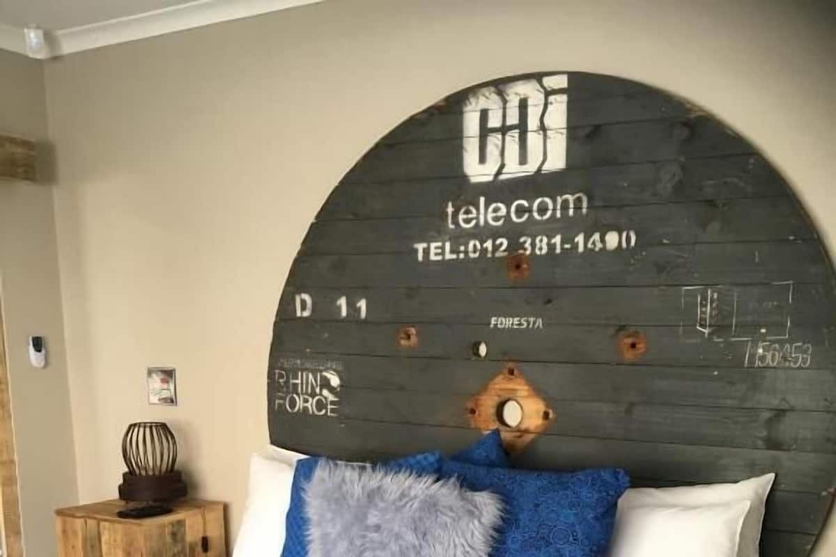Cama com cabeceira que exibe um logotipo e informações de contato, travesseiro fofo e travesseiro azul estampado.