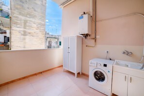 Uma lavanderia com máquina de lavar, secadora e aquecedor de água.