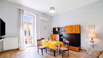 Uma sala de estar moderna com área de jantar, TV de tela plana, sofá e abajur.