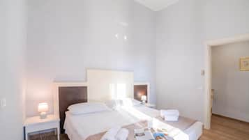 Quarto de hotel com uma cama grande, duas mesas de cabeceira e uma porta.