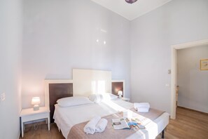 Quarto de hotel com uma cama grande, duas mesas de cabeceira e uma porta.
