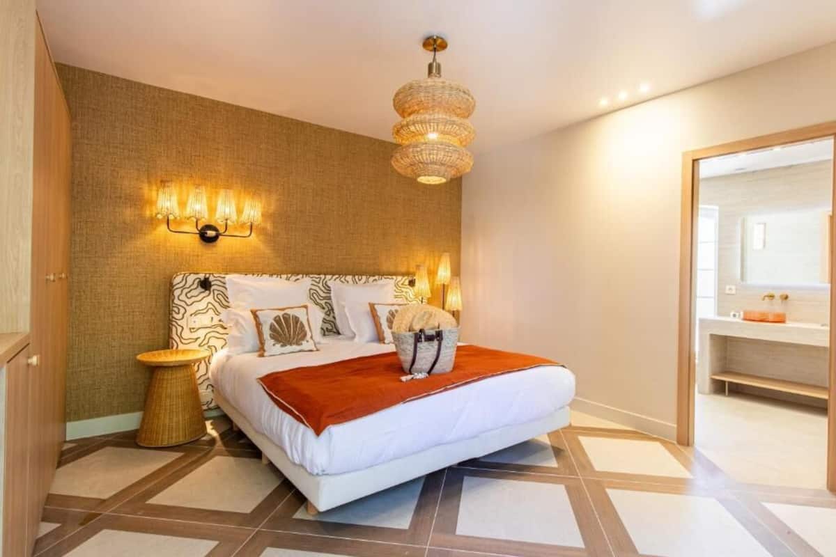 Quarto de hotel com cama, abajur, luminária na parede e espelho.