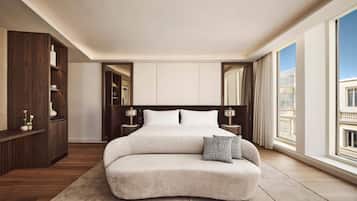 Quarto moderno com cama grande, roupeiro embutido, abajures e vista para a cidade.