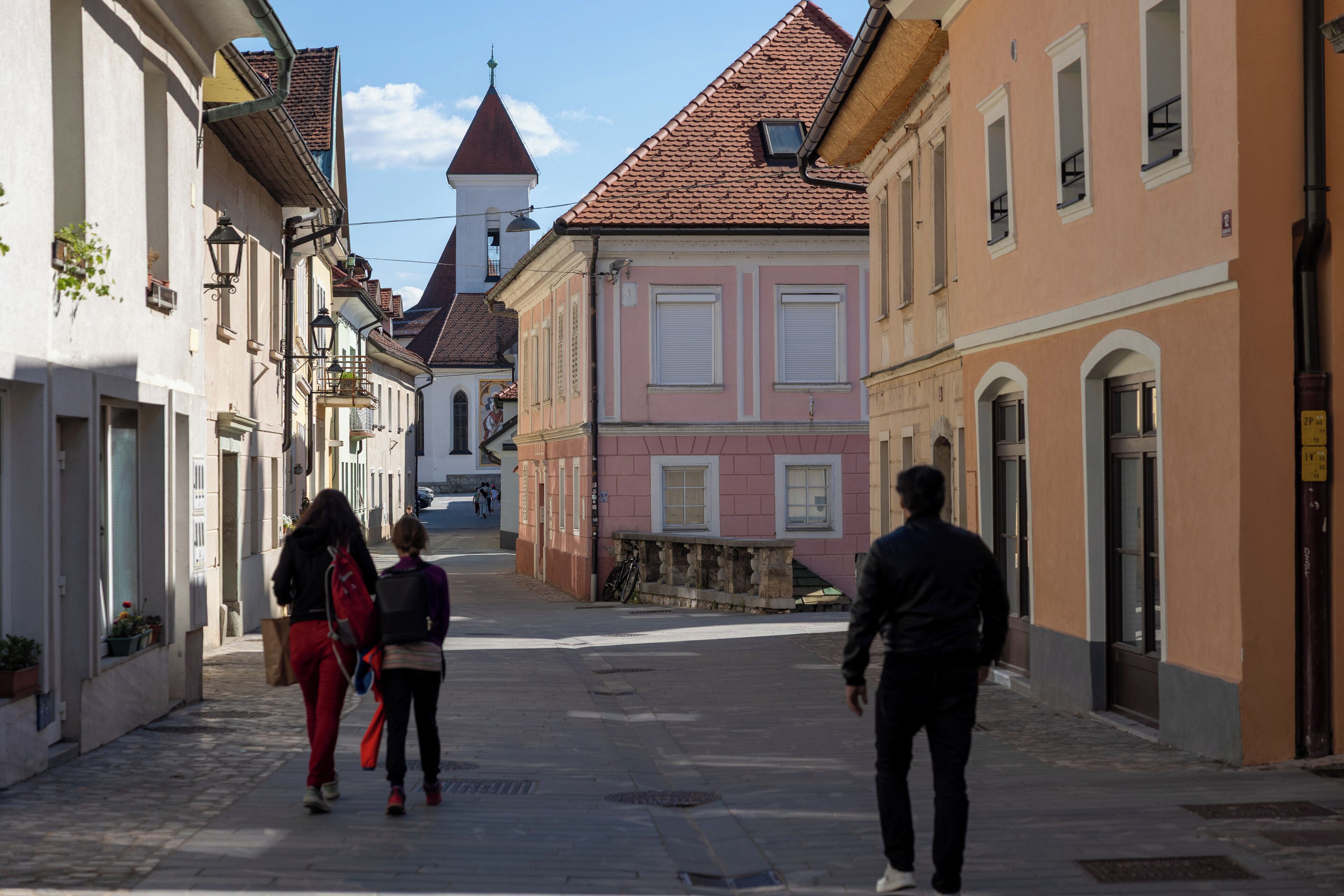 Uma rua estreita com edifícios históricos, o campanário de uma igreja e um céu limpo.