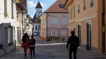 Uma rua estreita com edifícios históricos, o campanário de uma igreja e um céu limpo.