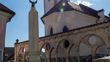 Um edifício histórico com uma torre imponente, um monumento central e uma série de arcos.