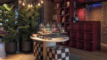 Um interior moderno com uma mesa redonda, pufes xadrez, uma parede de tijolos e uma estante vermelha.