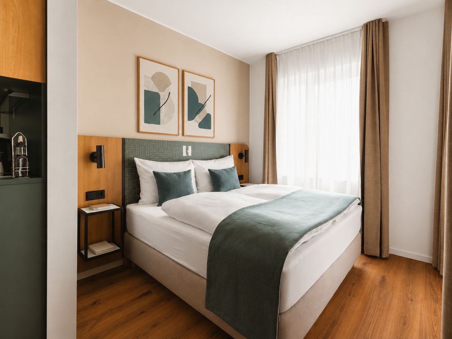Quarto de hotel moderno com uma cama grande, cabeceira de madeira, duas mesas de cabeceira, uma luminária de parede e uma janela com cortinas.