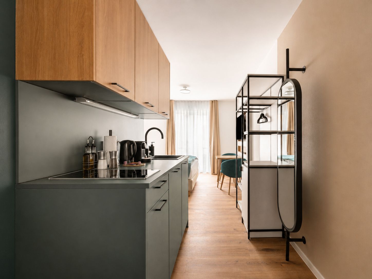 Cozinha compacta com eletrodomésticos modernos, área de jantar com mesa e cadeiras, e uma estante embutida.