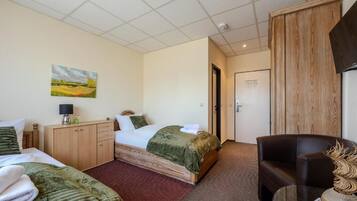 Quarto de hotel com duas camas, um guarda-roupa de madeira, uma televisão e um quadro na parede.