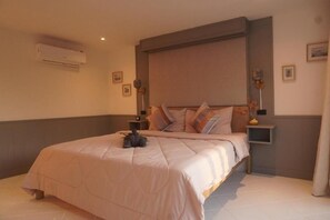 Quarto com cama, mesas de cabeceira, ar condicionado e obras de arte nas paredes.