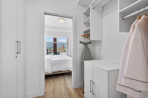 Quarto com cama, guarda-roupa, espelho e vista para o exterior.