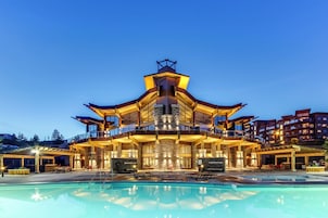Um hotel com vários andares e uma piscina na frente.