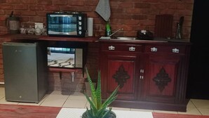 Uma cozinha com parede de tijolos, micro-ondas, geladeira e armários de madeira.