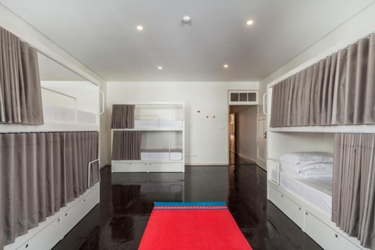 Quarto com beliches, cômoda branca e tapete vermelho.