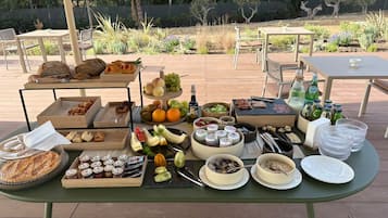Buffet ao ar livre com diversos alimentos e bebidas dispostos em mesas.