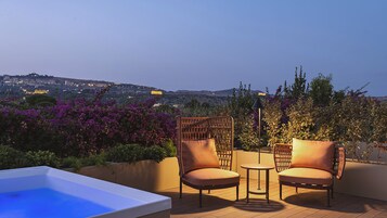 Terraço no telhado com duas cadeiras de vime, uma mesa pequena e uma piscina retangular branca.