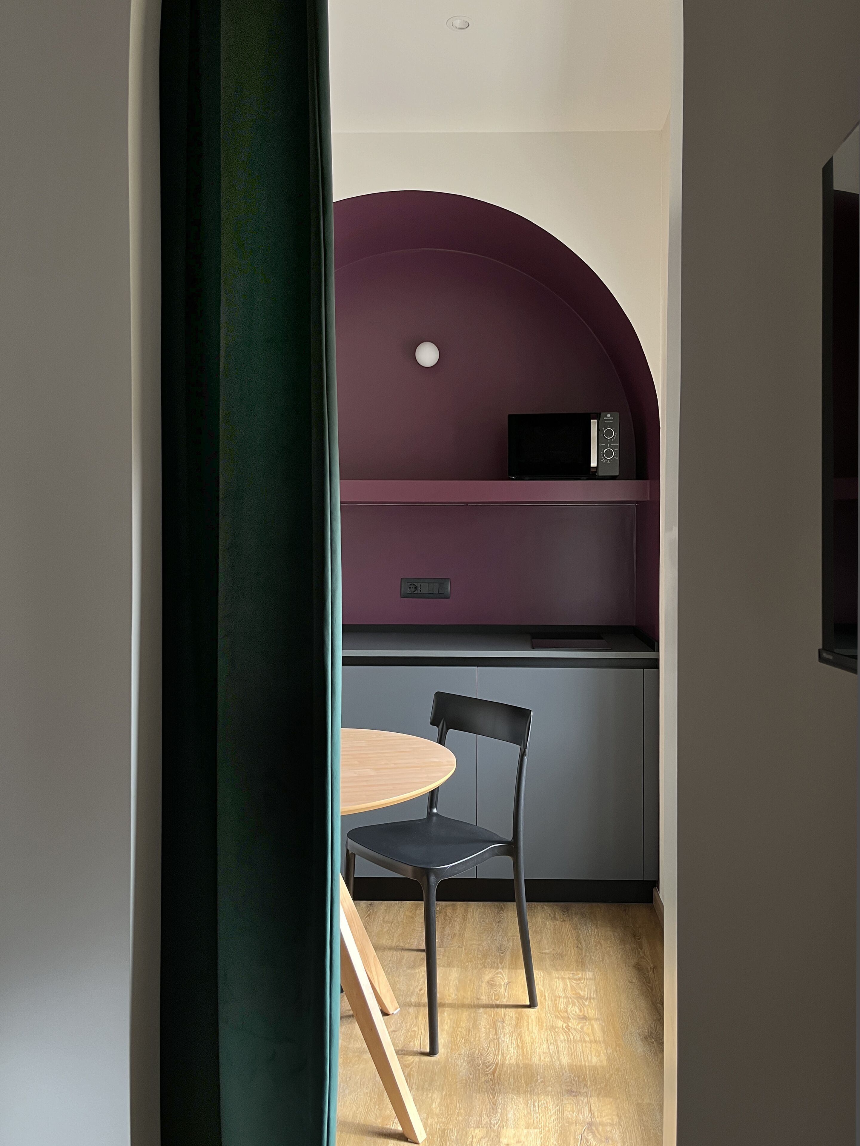 Quarto com mesa de jantar, uma cadeira, televisão e cozinha com arco roxo.