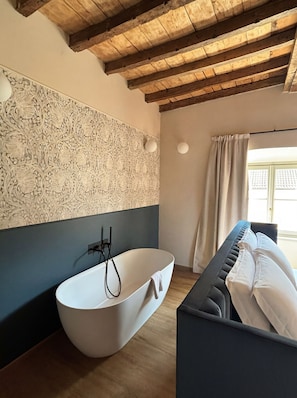 Um banheiro moderno com uma banheira independente, um banco escuro azul e um painel decorativo na parede.