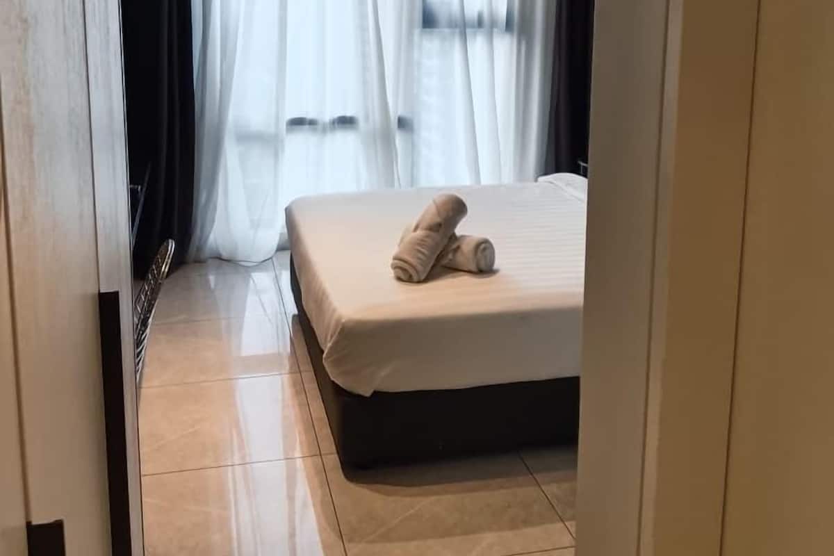 Quarto de hotel com cama, cortinas e luminária no teto.