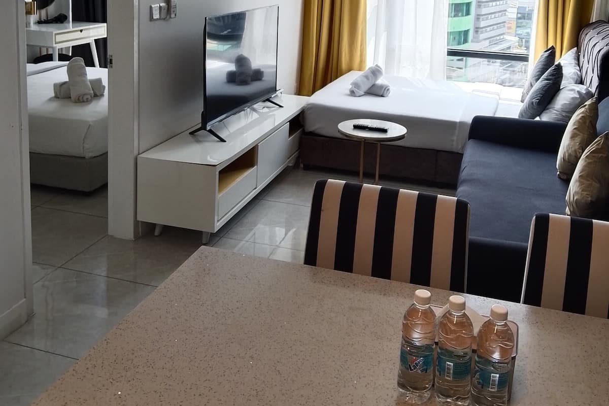 Quarto de hotel moderno com televisão, sofá, mesa de jantar e vista para a cidade.