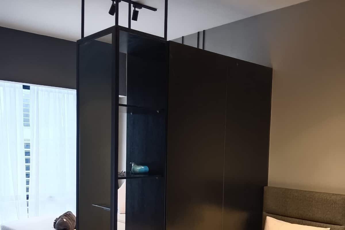 Quarto moderno com cama, área de estar e uma janela grande.