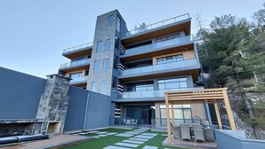 Um edifício com vários andares, varandas, um espaço de pátio com móveis de exterior e fachada de pedra.