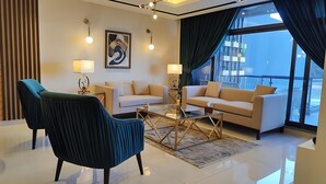 Uma sala de estar moderna com dois sofás, uma mesa de centro de vidro e uma poltrona azul.