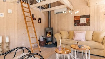 Um quarto acolhedor com interior em madeira, um sofá, uma escada, uma lareira e um candelabro.