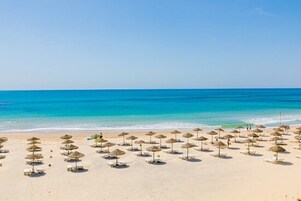 Uma praia privada, guarda-sóis de praia, bares na praia