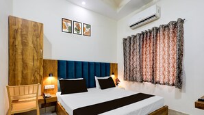 Quarto com cama, mesa de cabeceira, cadeira, obra de arte na parede e ar condicionado.